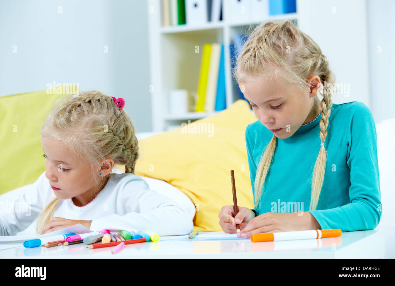 Portrait of lovely twins drawing with colorful pencils Stock Photo - Alamy