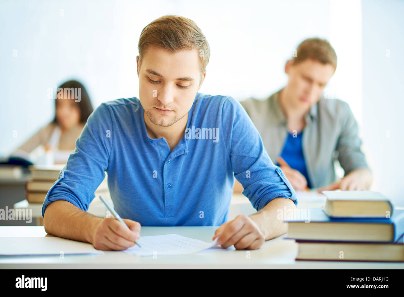 Portrait of handsome student carrying out test at lesson with ...
