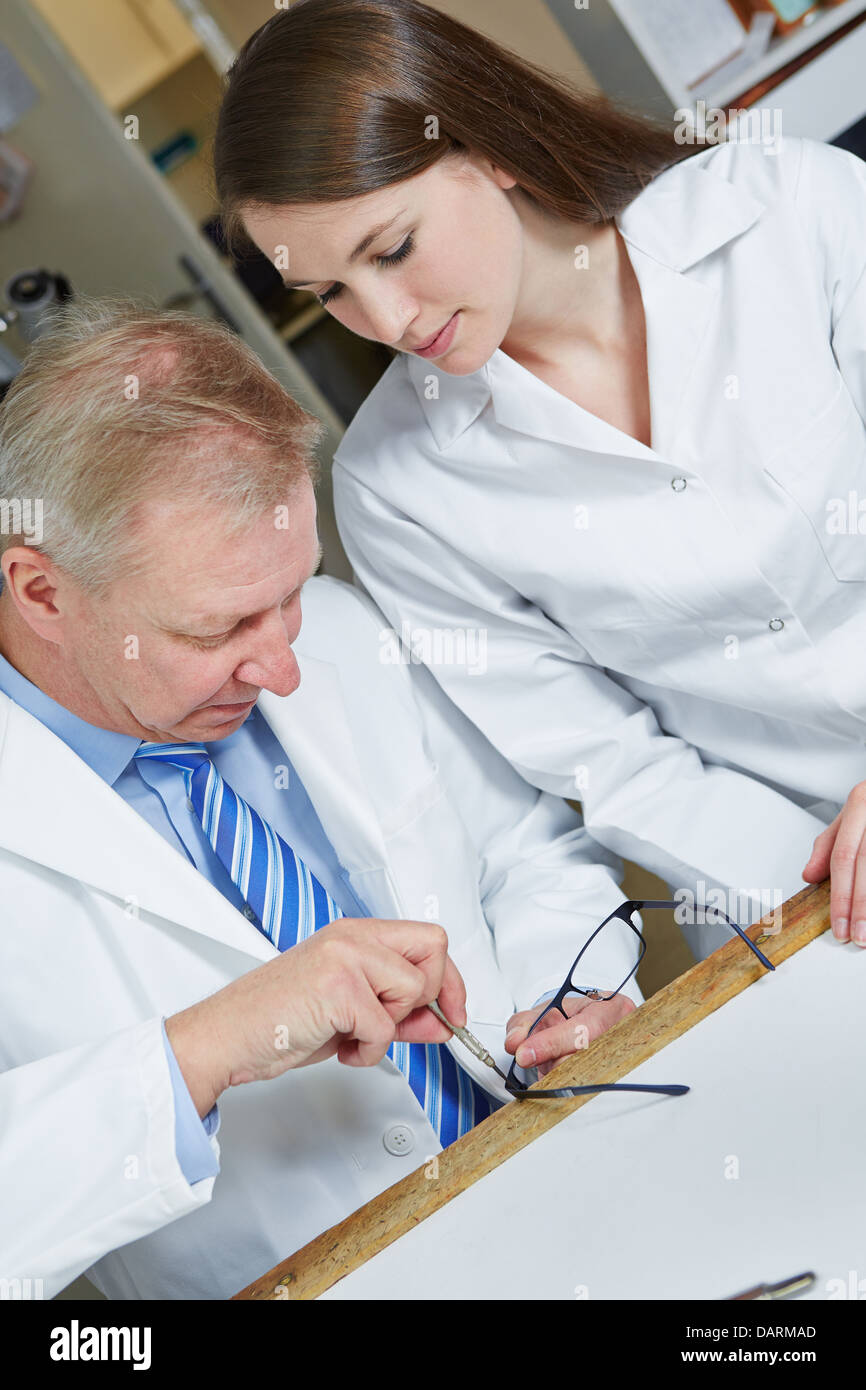 Optician with trainee fixing glasses in workshop Stock Photo - Alamy