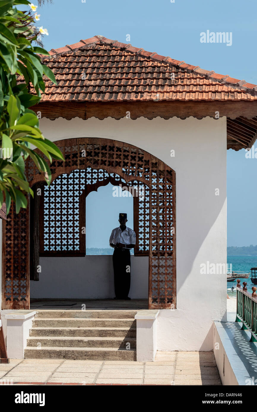Africa, Tanzania, Zanzibar, Stone Town. Guard standing in shade of ...
