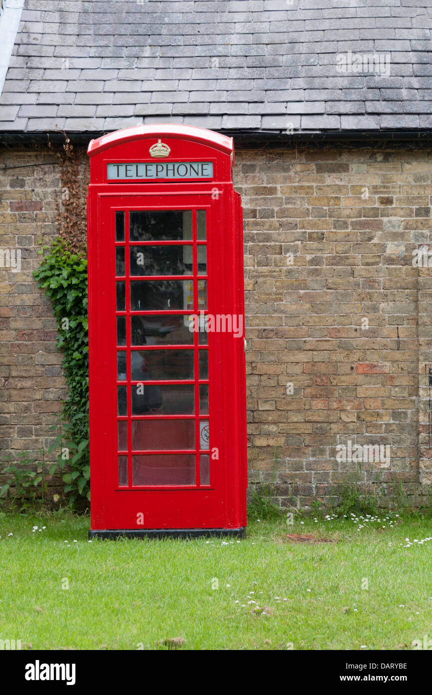A traditional red telephone box outside an old building in a village in ...