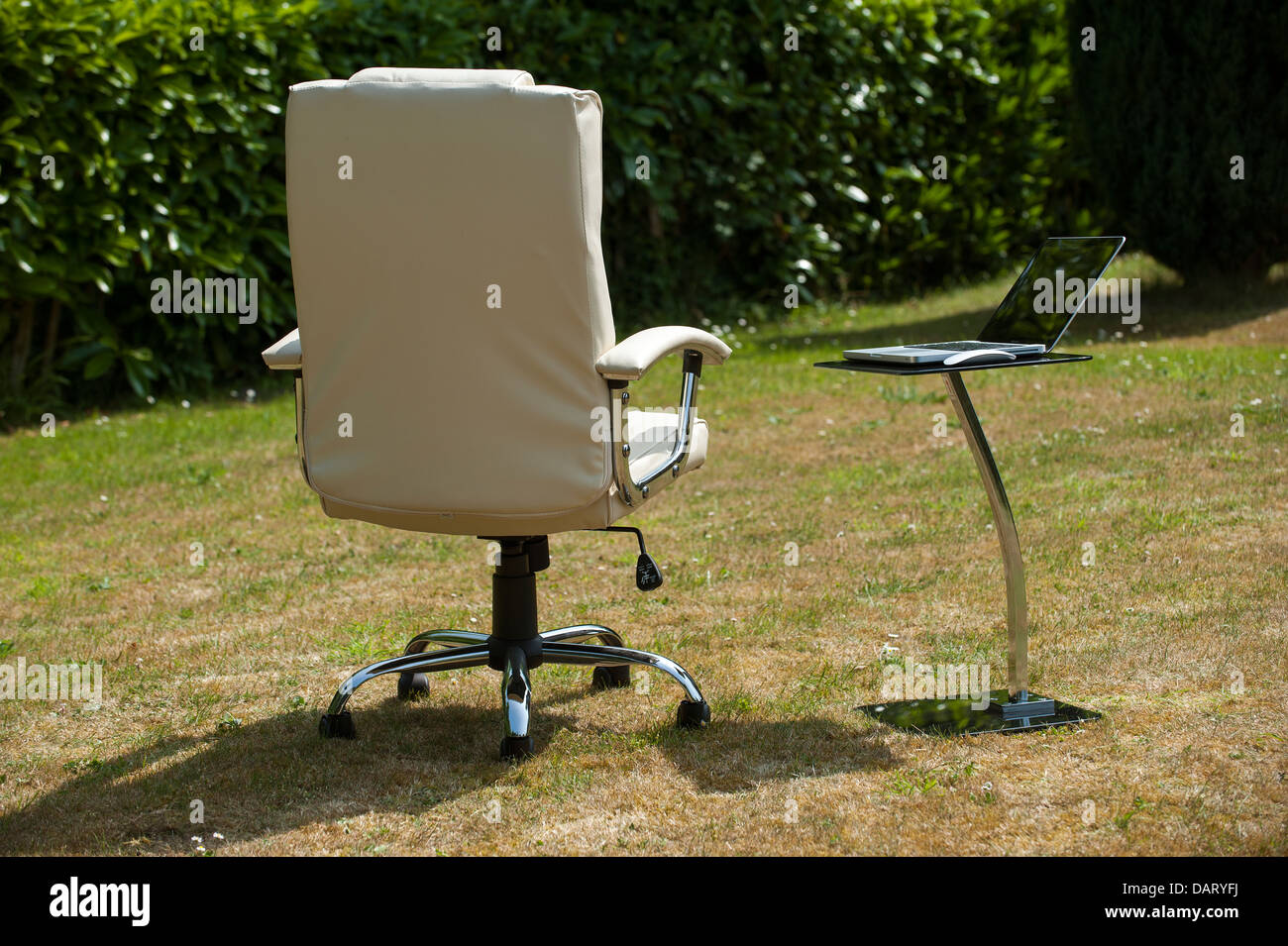 Garden office cream leather chair and laptop computer on a glass table ...