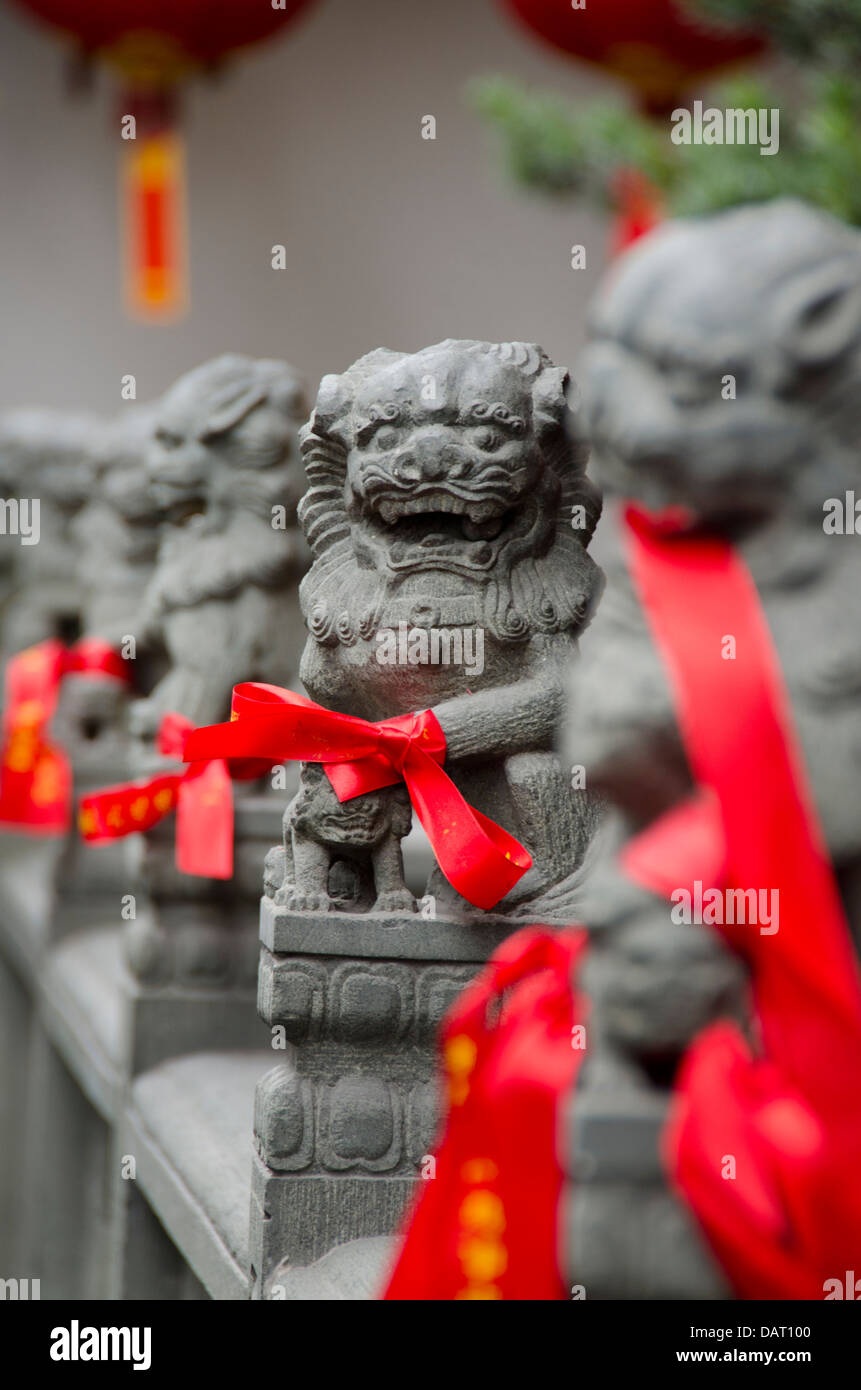 China, Shanghai, Jade Buddha Temple. Stone lion statues with red ribbon ...