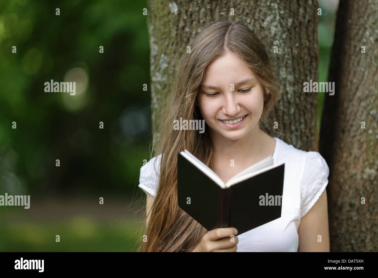 young girl reading book near tree, horizontal Stock Photo - Alamy