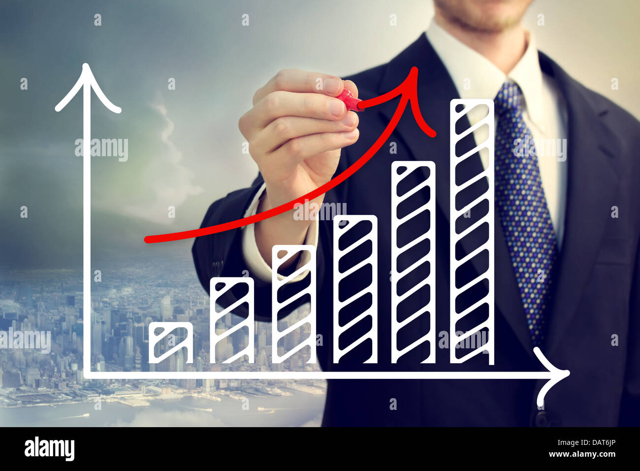 Businessman drawing a rising arrow over a bar graph above the city ...