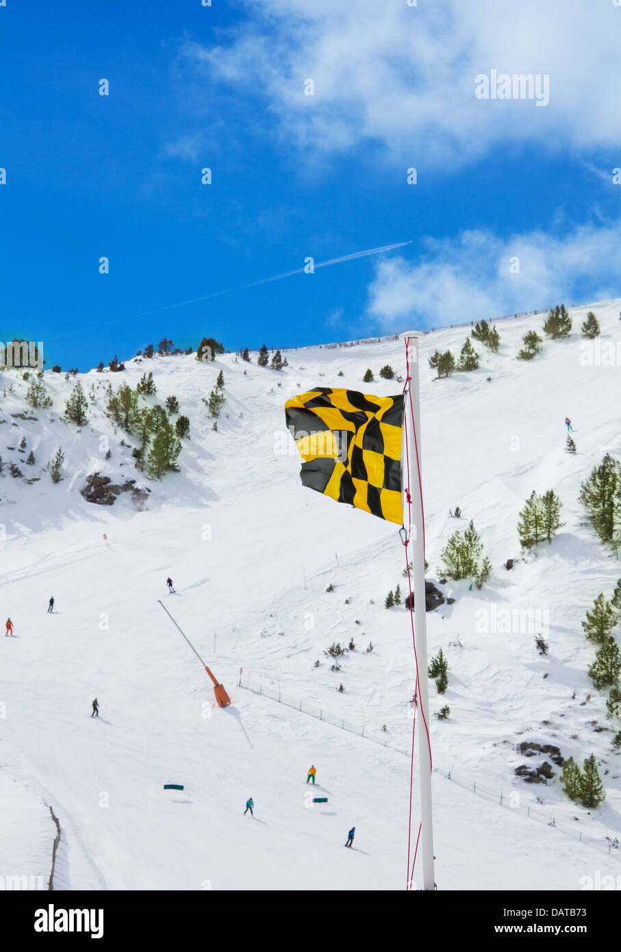 Avalanche warning flag with ski slope and piste on background with ...