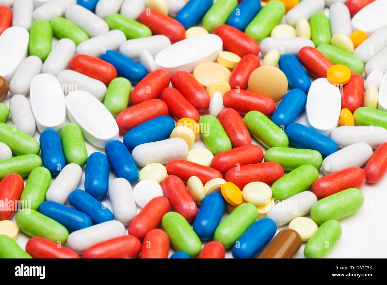 Many different pills and tablets of different colors laying in pile ...