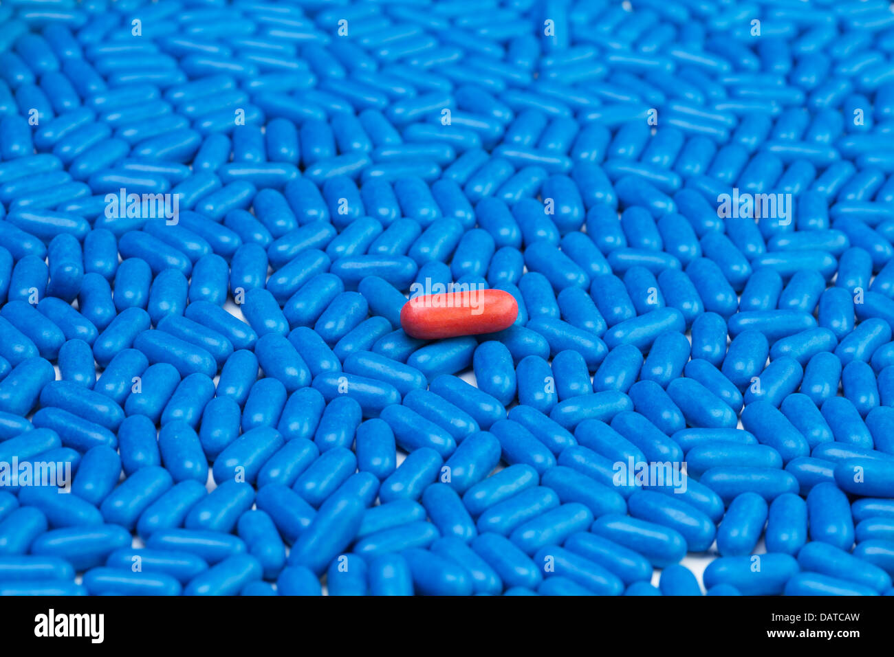 One red drug pill laying on many blue tablets Stock Photo - Alamy