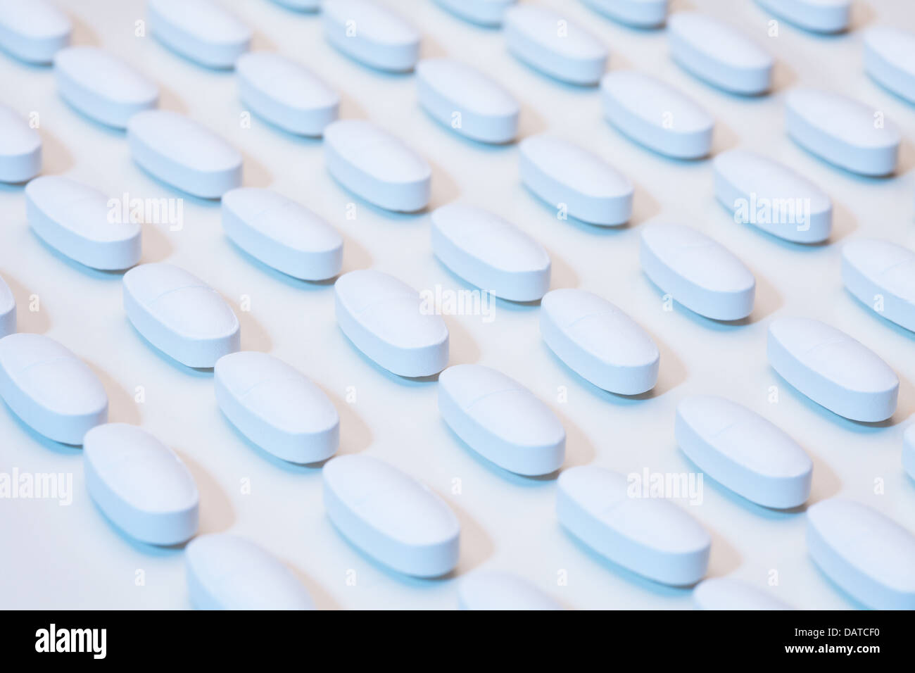 White long tablet drugs laying in a row pattern on white table under ...