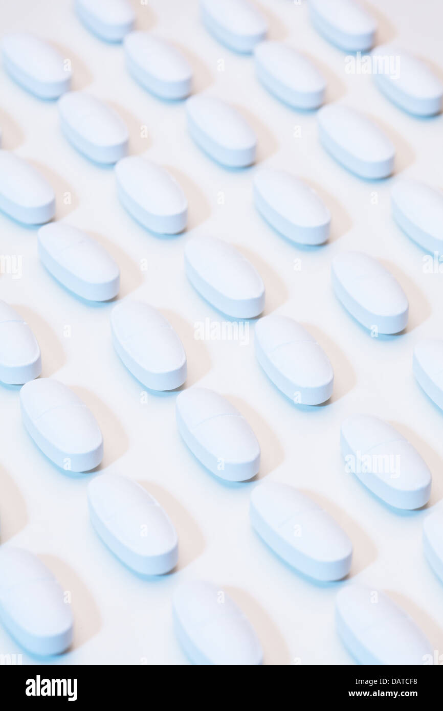 White long tablet drugs laying in a row pattern on white lab table ...