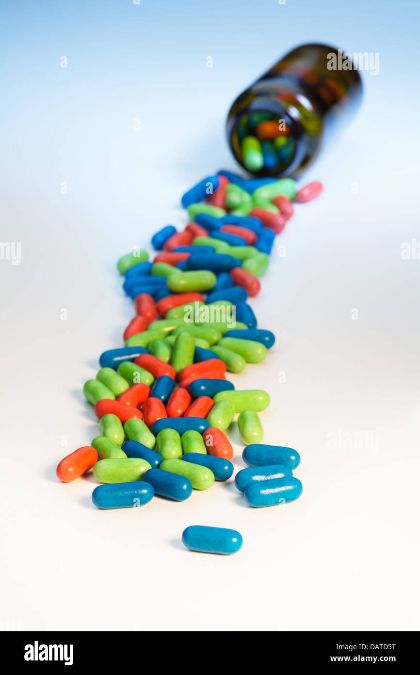 Different color drugs in pills scattered from the jar Stock Photo - Alamy