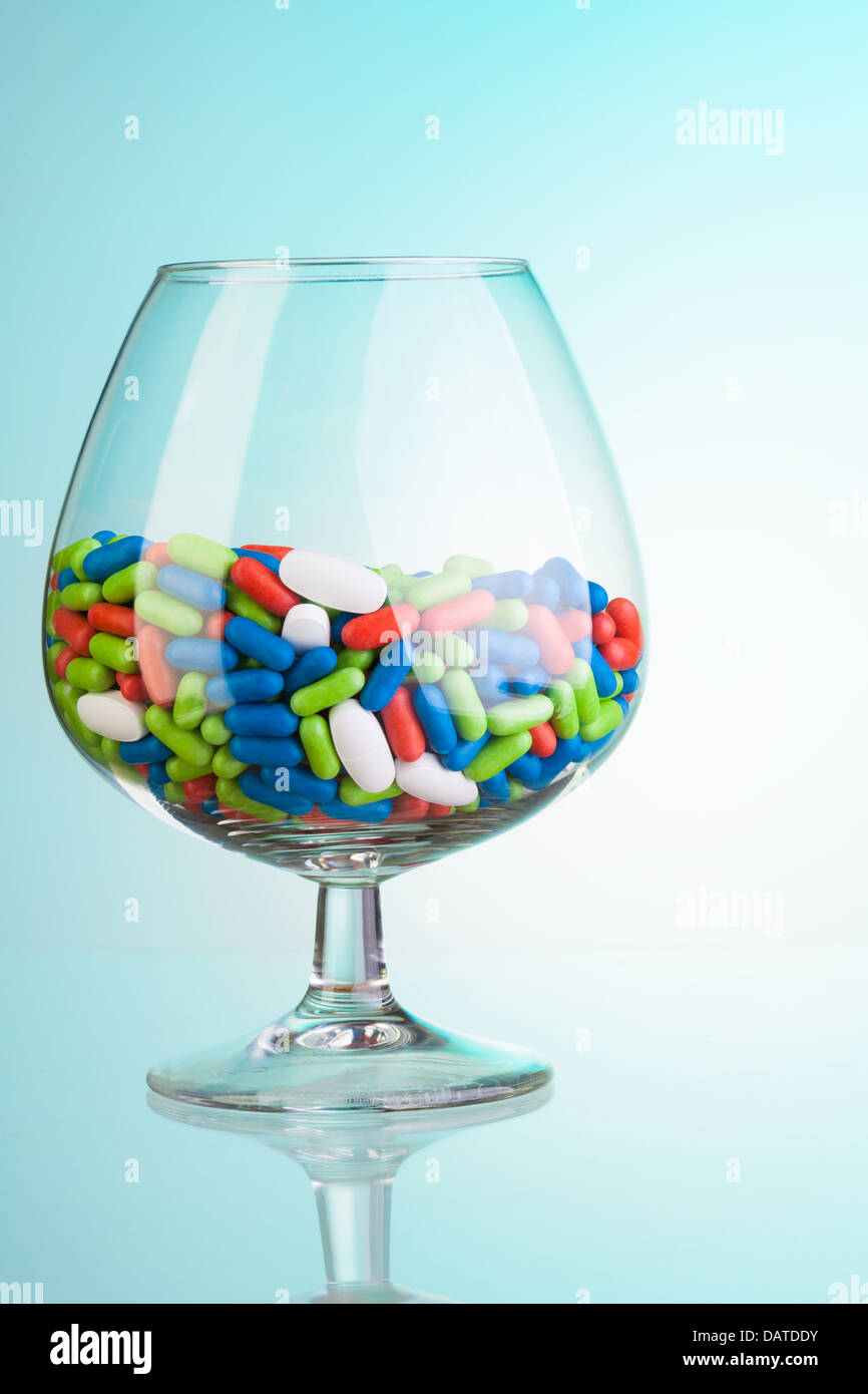 Drug pills of different color in the whisky glass as a concept of ...