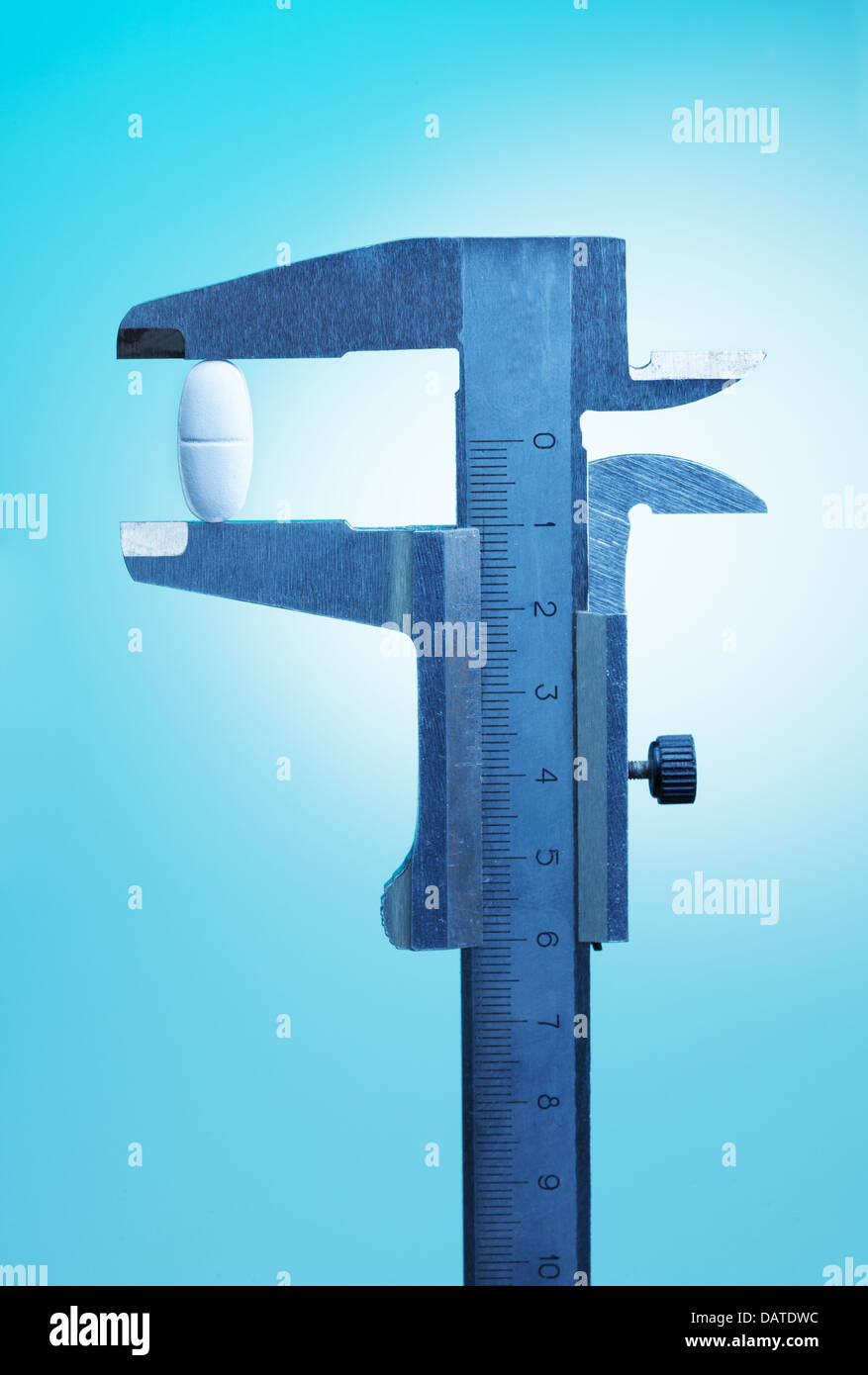 Caliper measures size of white pill, on blue Stock Photo - Alamy