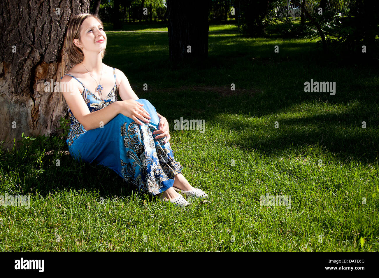 beautiful woman sitting under a tree in park Stock Photo - Alamy