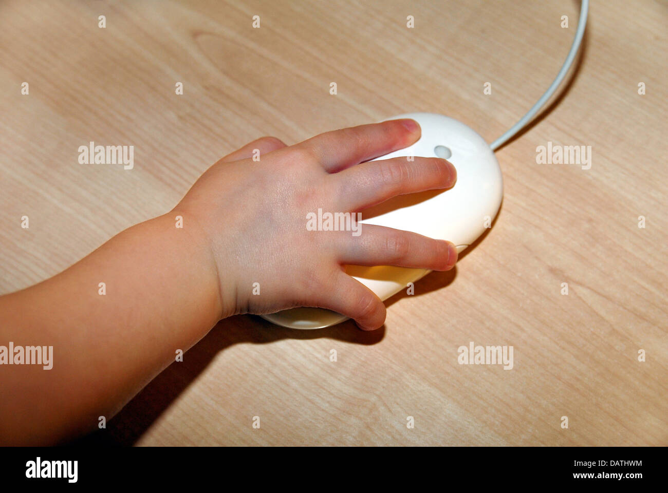 A childs hand operating a white computer mouse. ( Apple Mighty Mouse ...