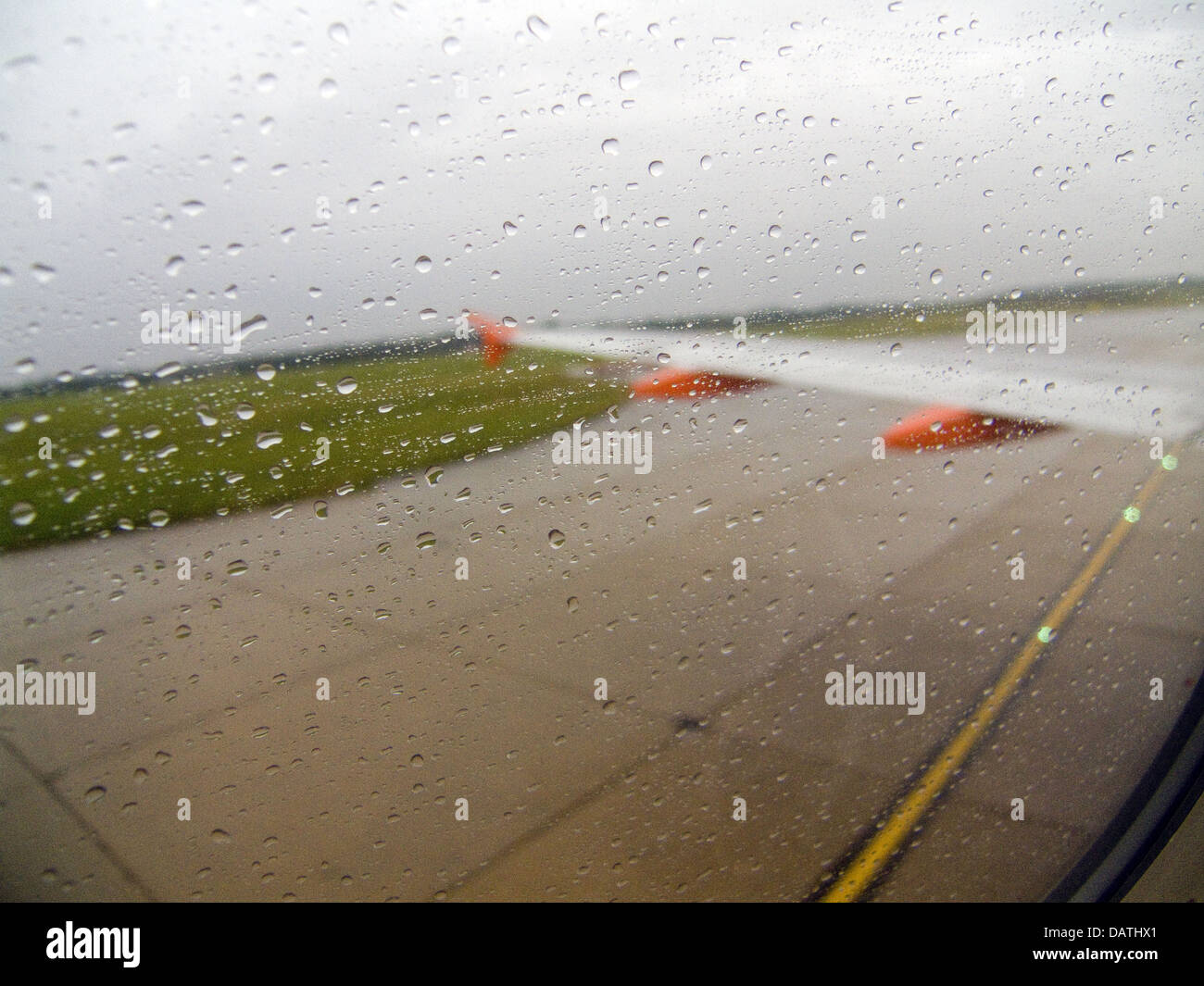 An aircraft wing seen through rain covered window during take-off ...