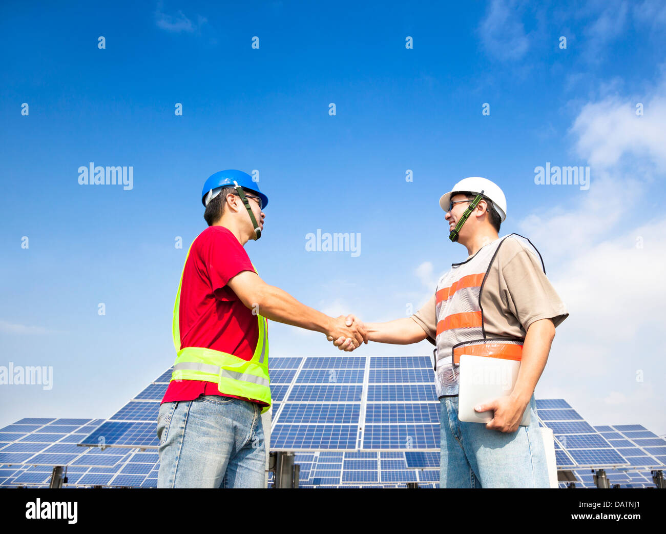 two engineers handshaking before large solar power station Stock Photo ...