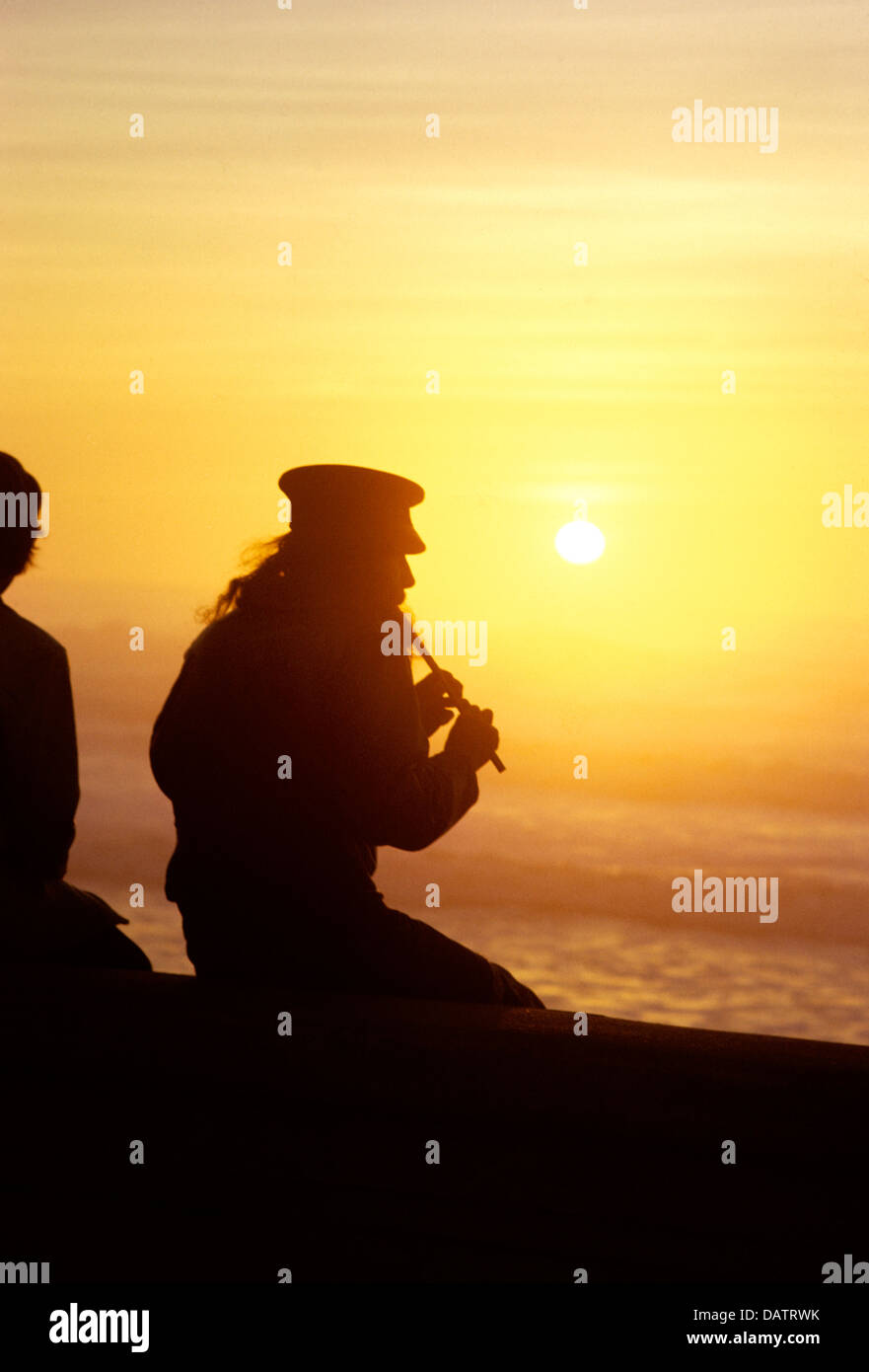 Hippie musician playing flute at sunset at San Francisco beach in ...