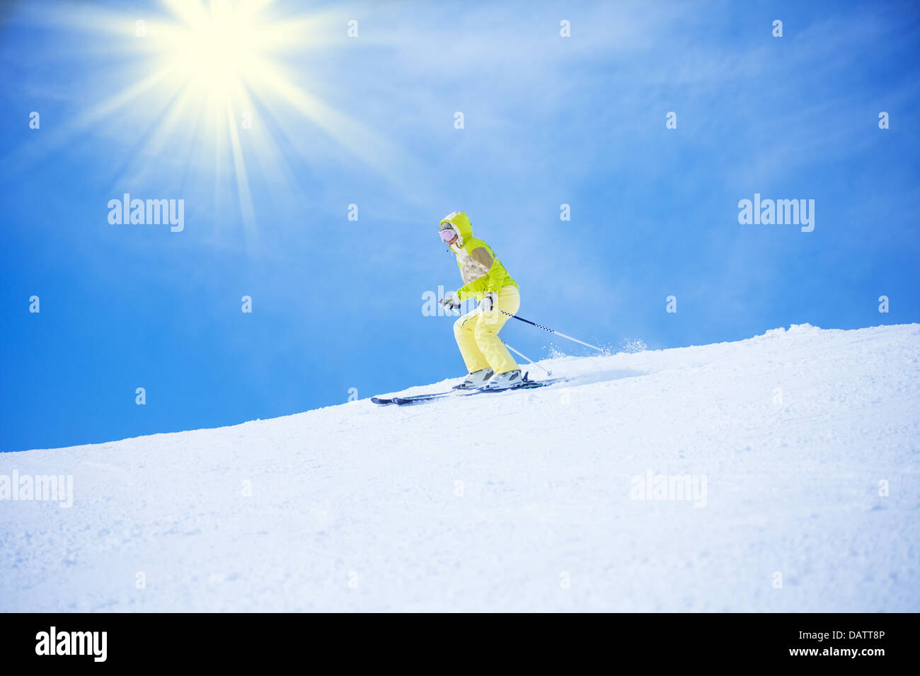 Young happy woman sliding downhill with clean white snow and blue sky ...