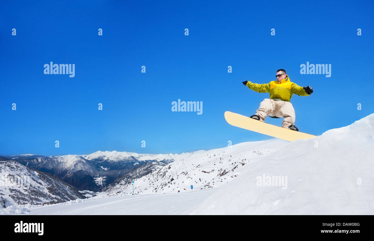 Cute handsome snowboarder man jumping from trampoline on snowboard in ...