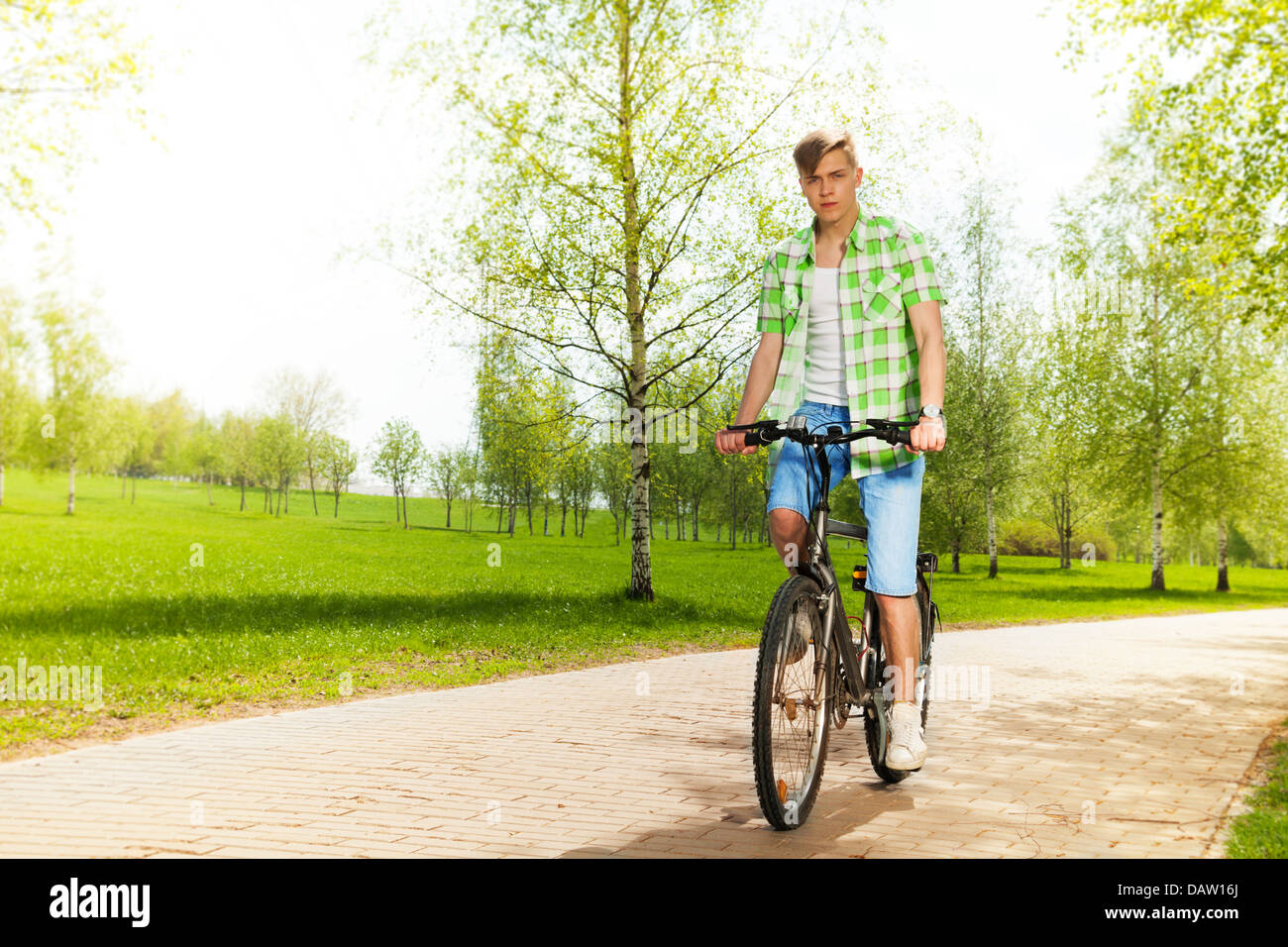 Young man riding a bike on the road in park Stock Photo - Alamy