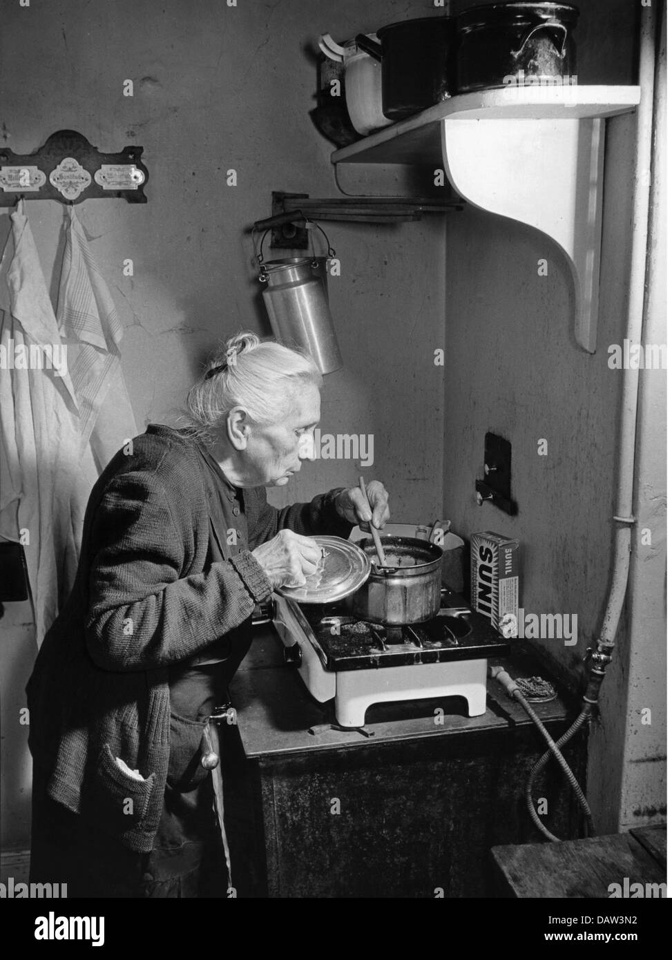 household, cooking and baking, old woman at cooker stirring in pot ...