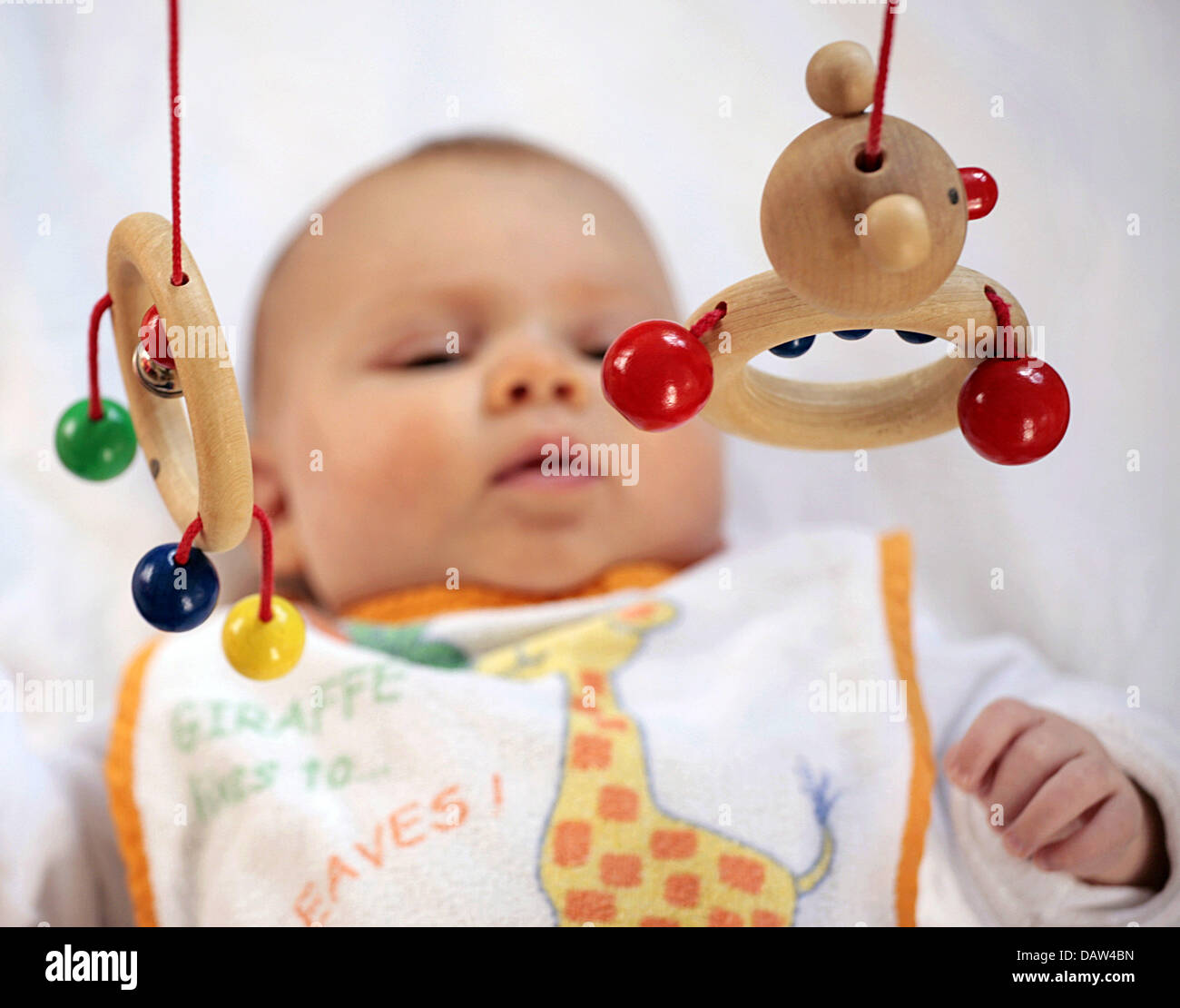 An almost three-year old baby is pictured with dangling toys in ...