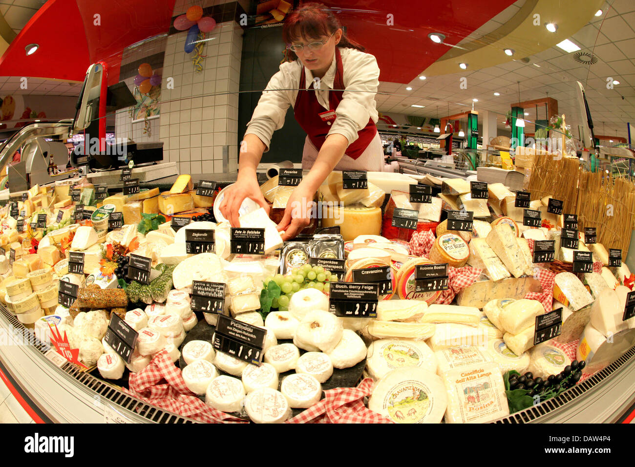 An employee arranges cheese in a refrigerated shelf at a remodeled REWE ...