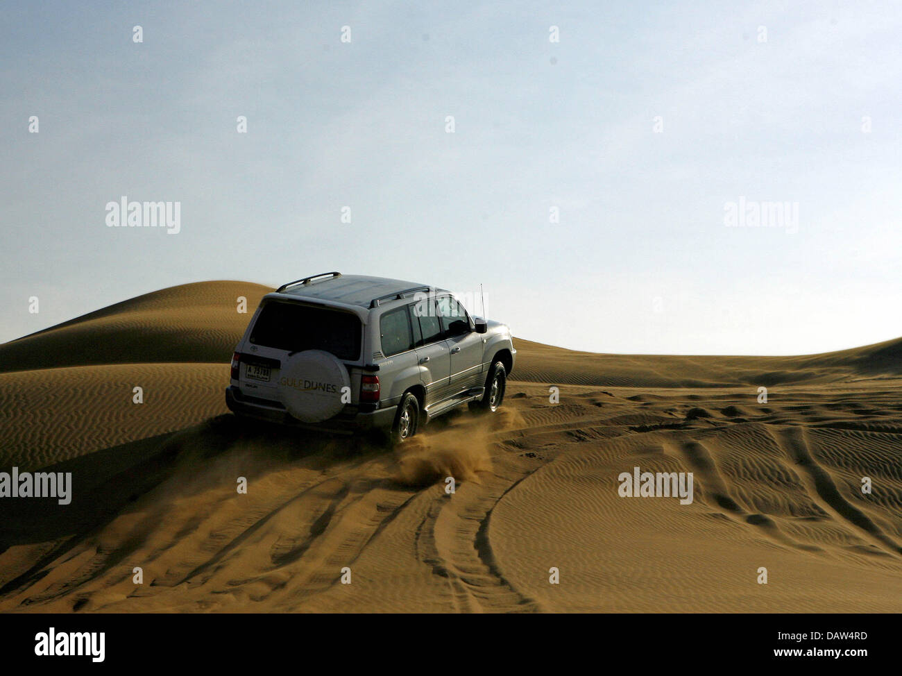A four-wheel drive with tourists is pictured in the dunes at a desert ...