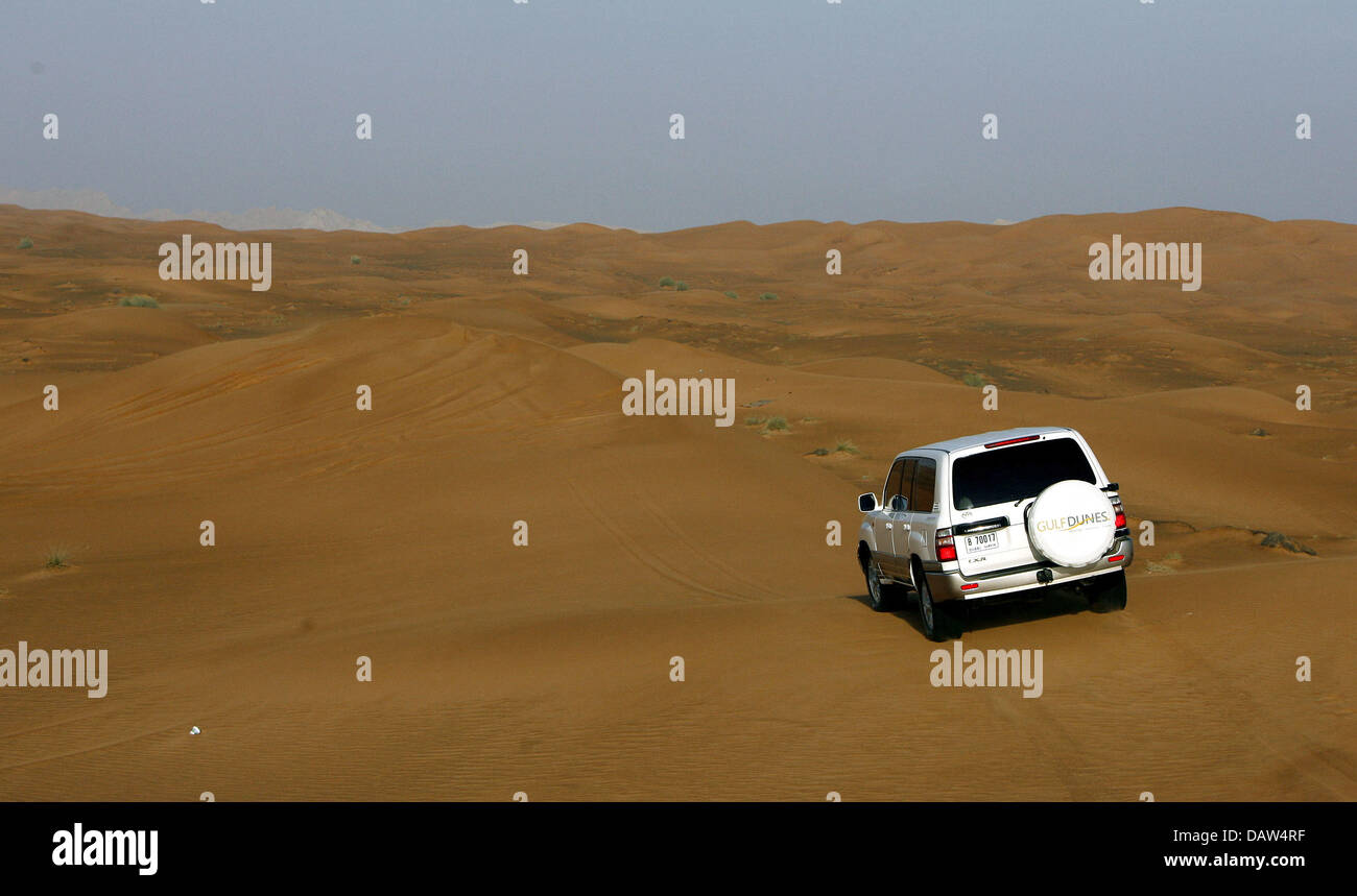 A four-wheel drive with tourists is pictured in the dunes at a desert ...
