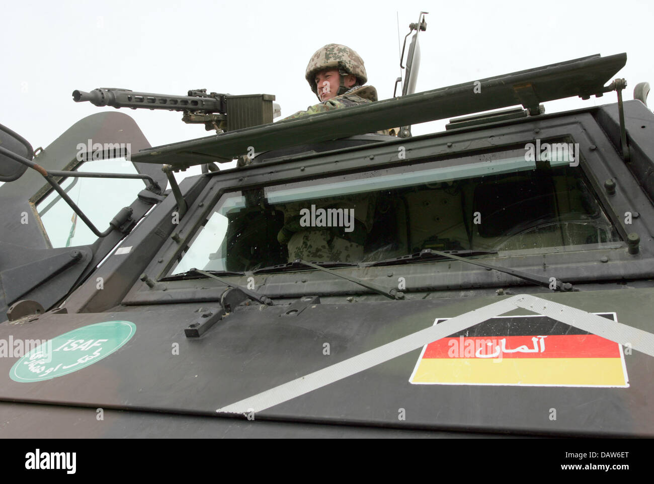 A German ISAF soldier looks out of an armoured car with a machine gun ...