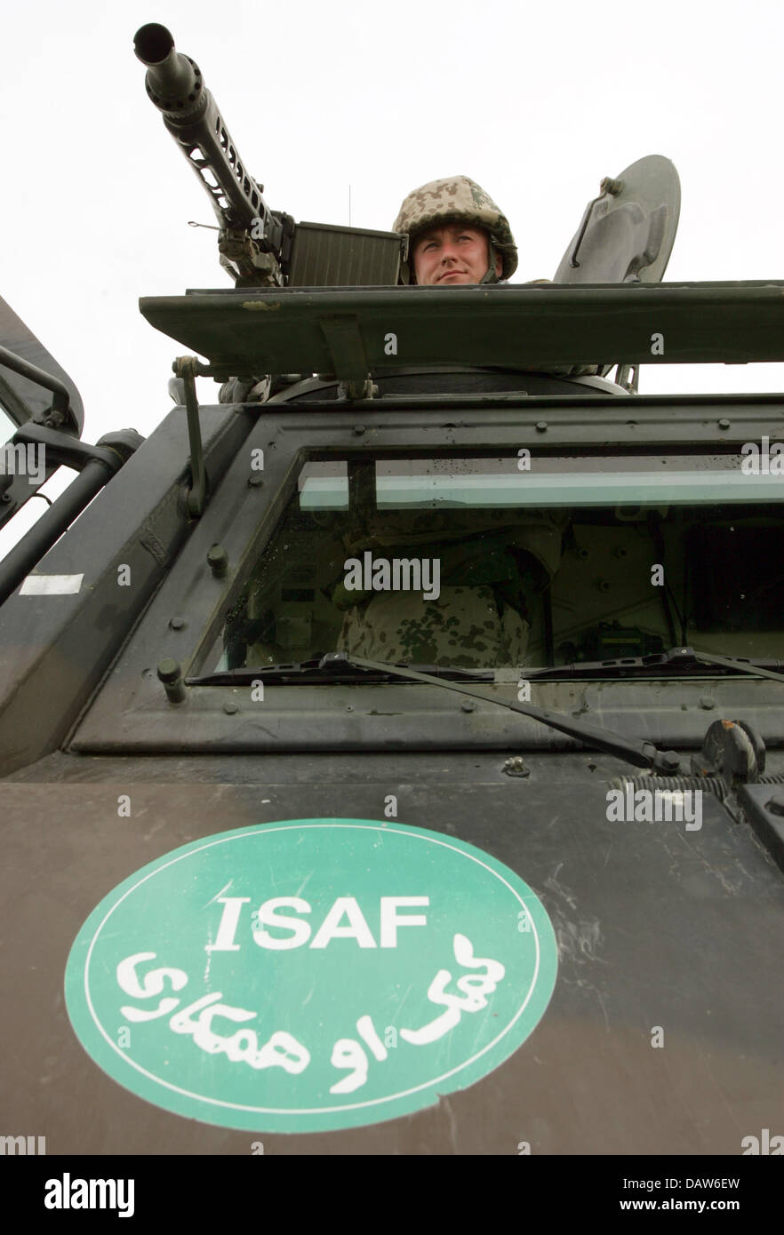 A German ISAF soldier looks out of an armoured car next to a machine ...