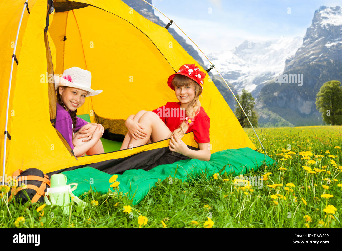 Two happy laughing little girls sitting in camping tent in mountain ...
