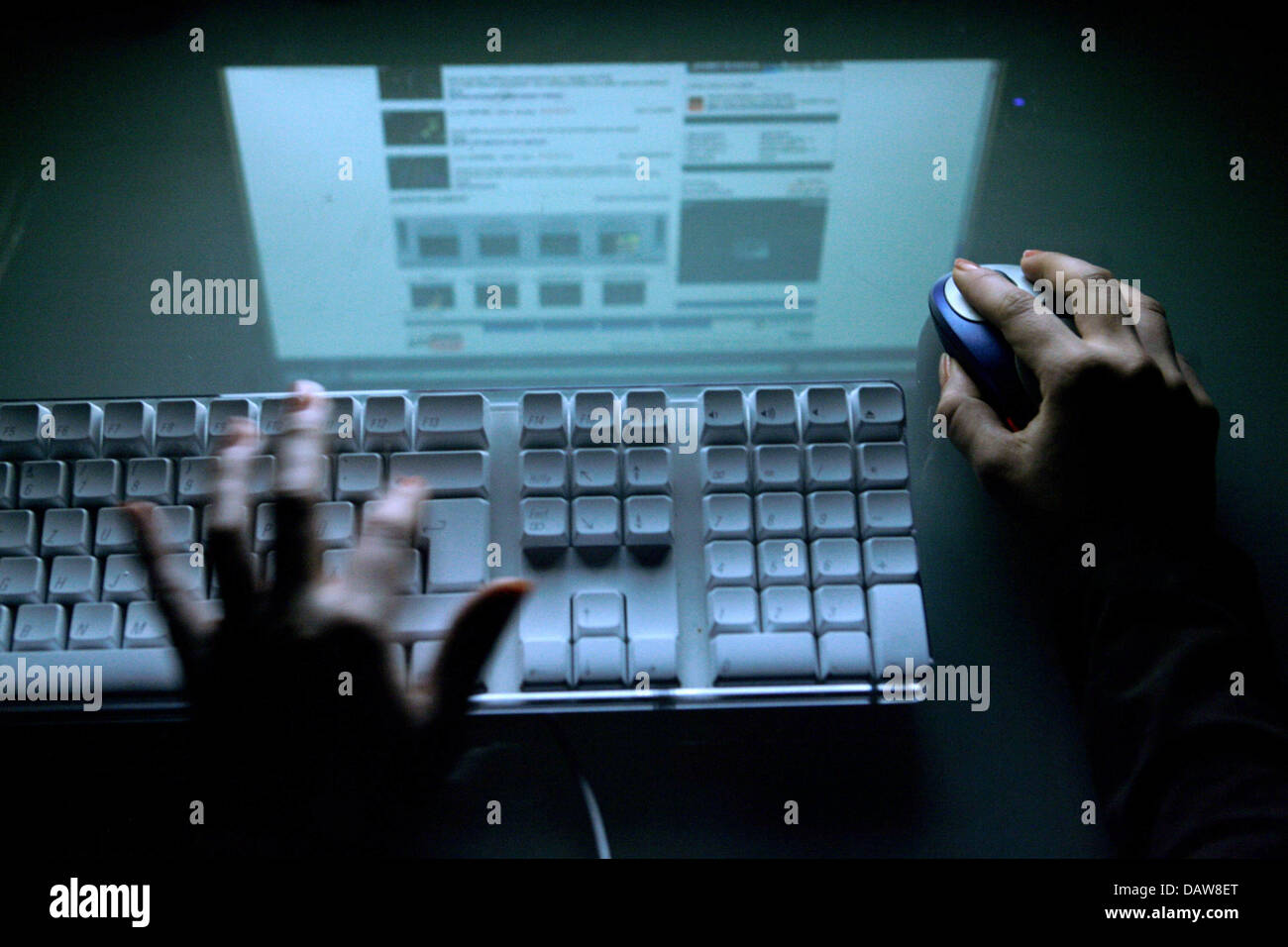 A woman types with her left hand on the keyboard and uses the mouse ...