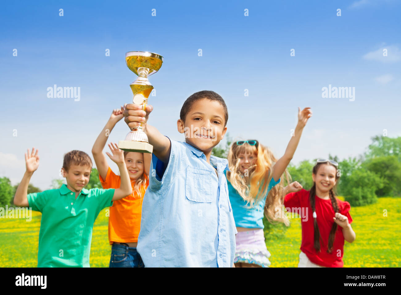 Portrait of black happy smiling little boy holding prize cup with his ...