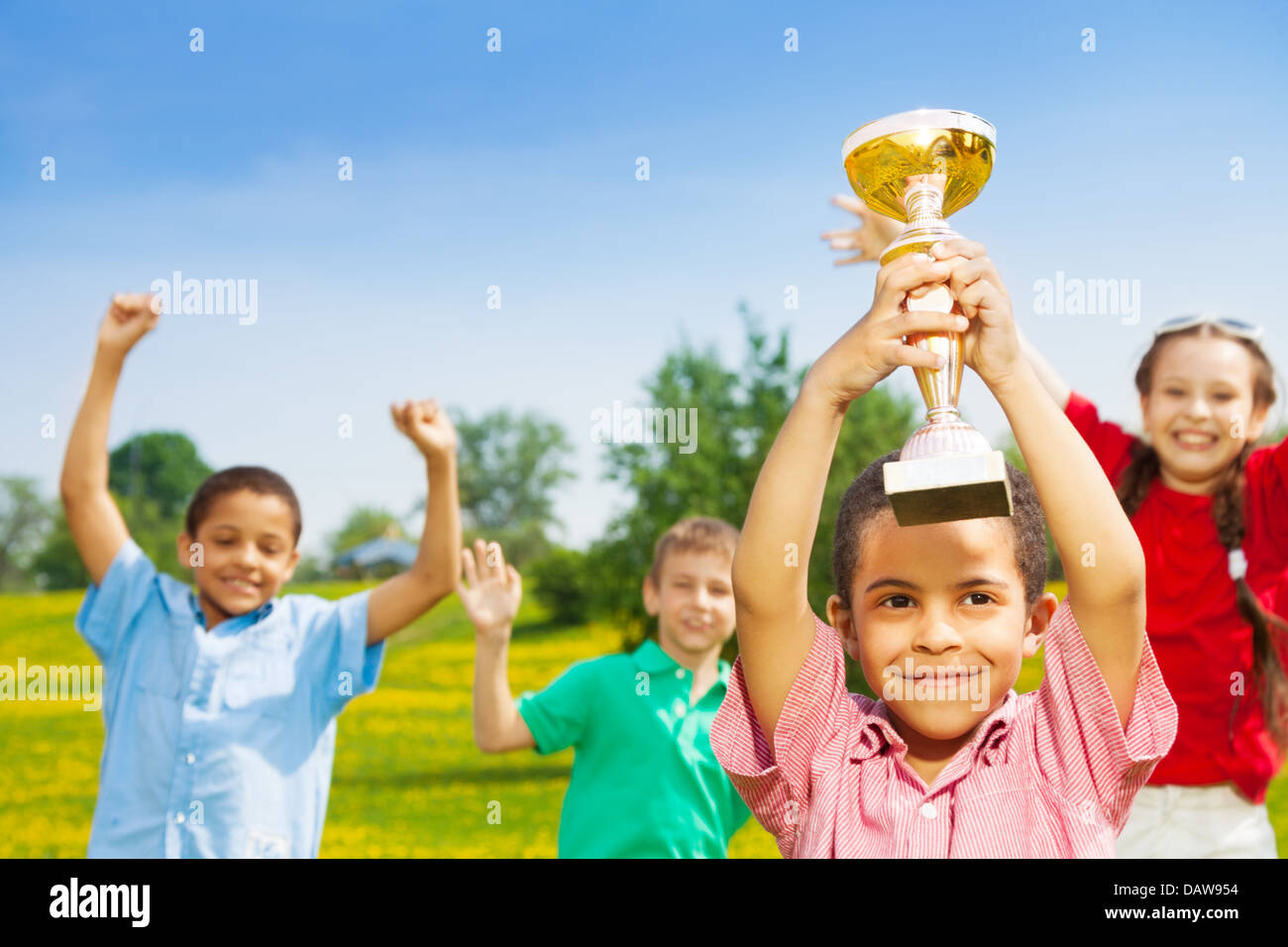 Close shoot of black happy smiling little boy holding prize cup with ...