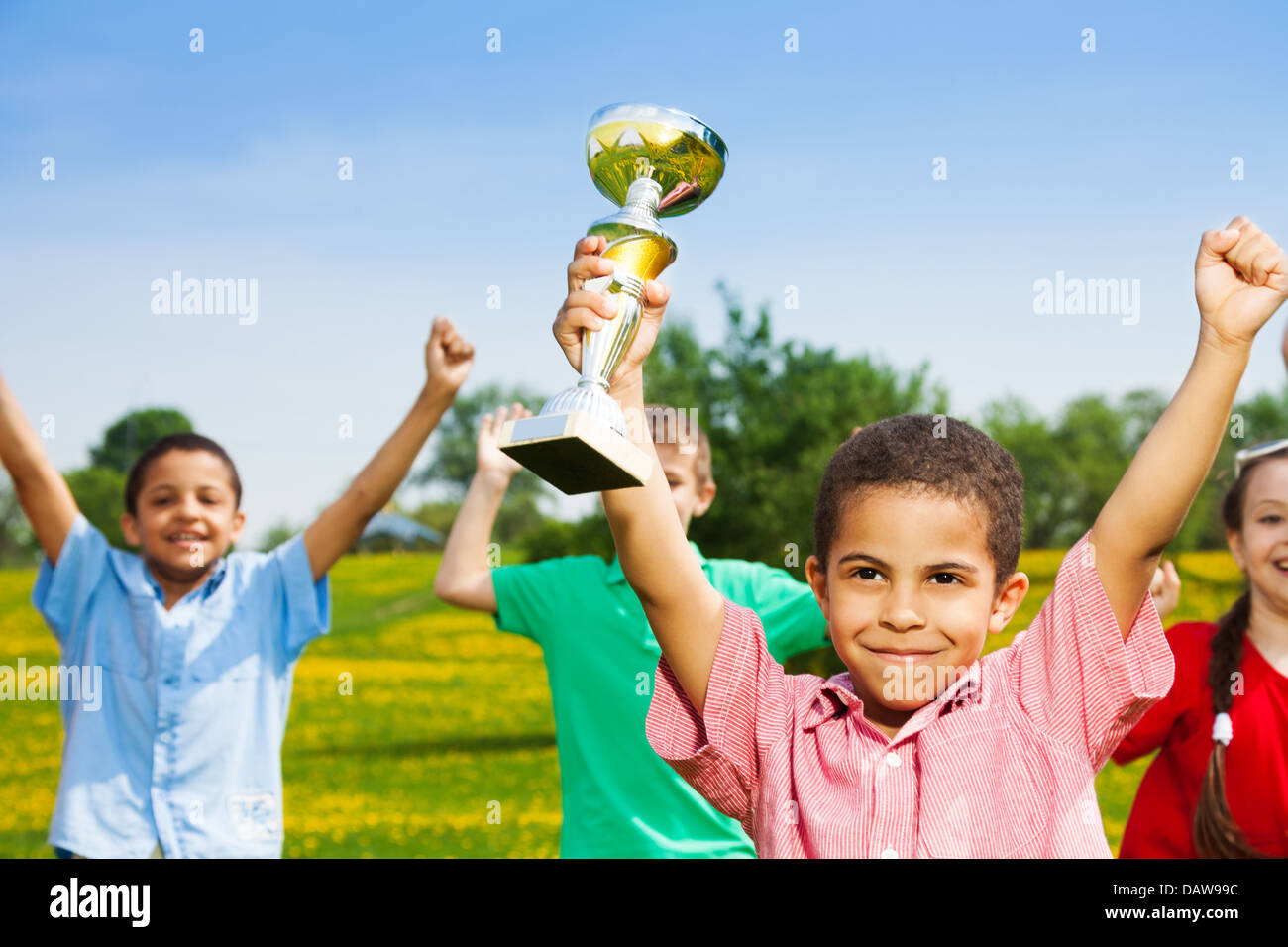 Close shoot of black happy smiling little boy holding prize cup in ...