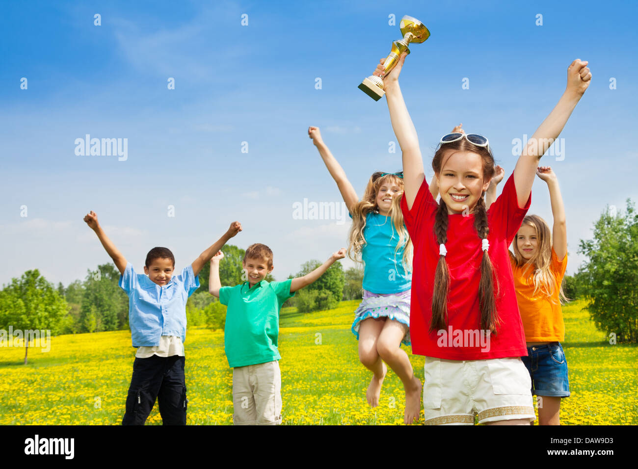 Group of happy kids of winner team with leader holding prize award cup ...
