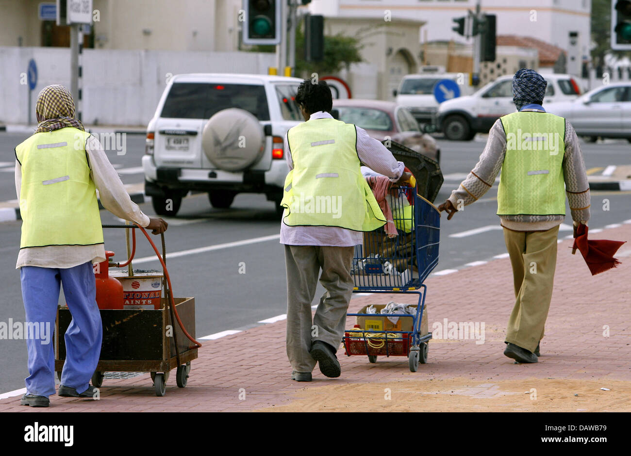 The picture shows three expatriate migrant workers pushing carts at a ...