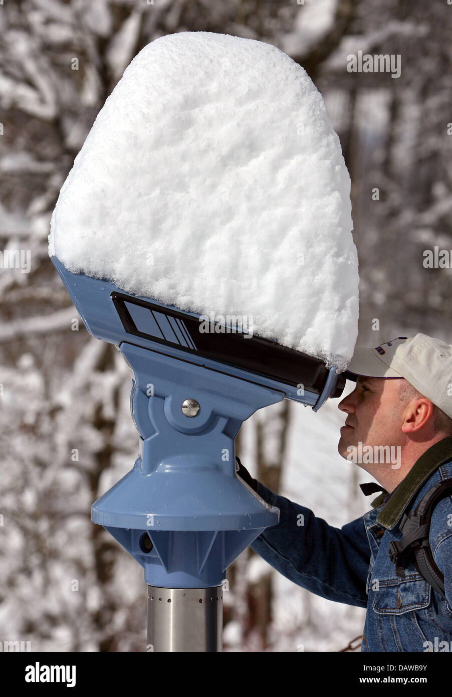 A tourist looks through a telescope covered with a thick layer of snow ...