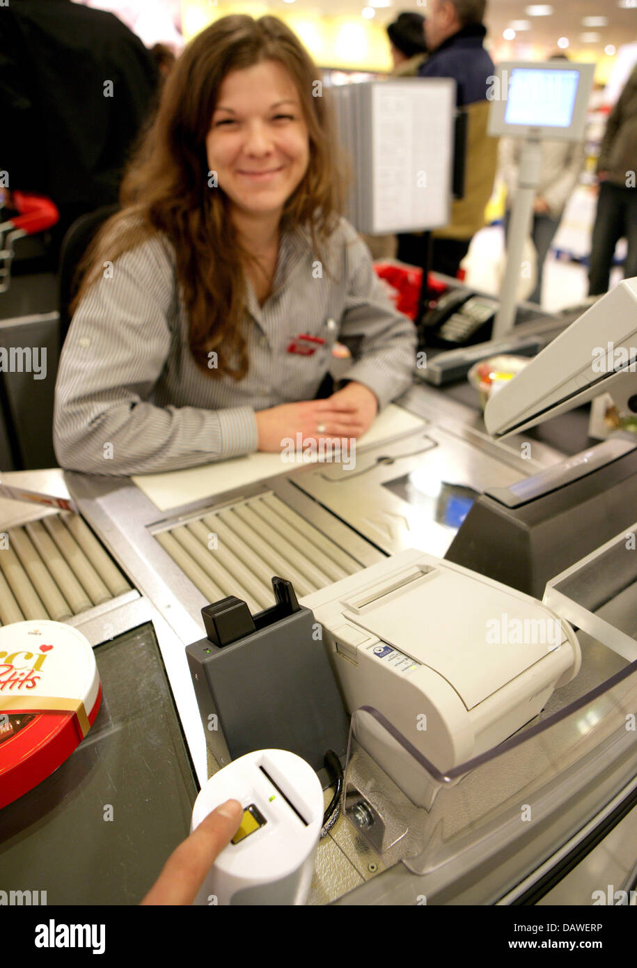 The picture shows a customer using the finger tip scanner at a cashier ...