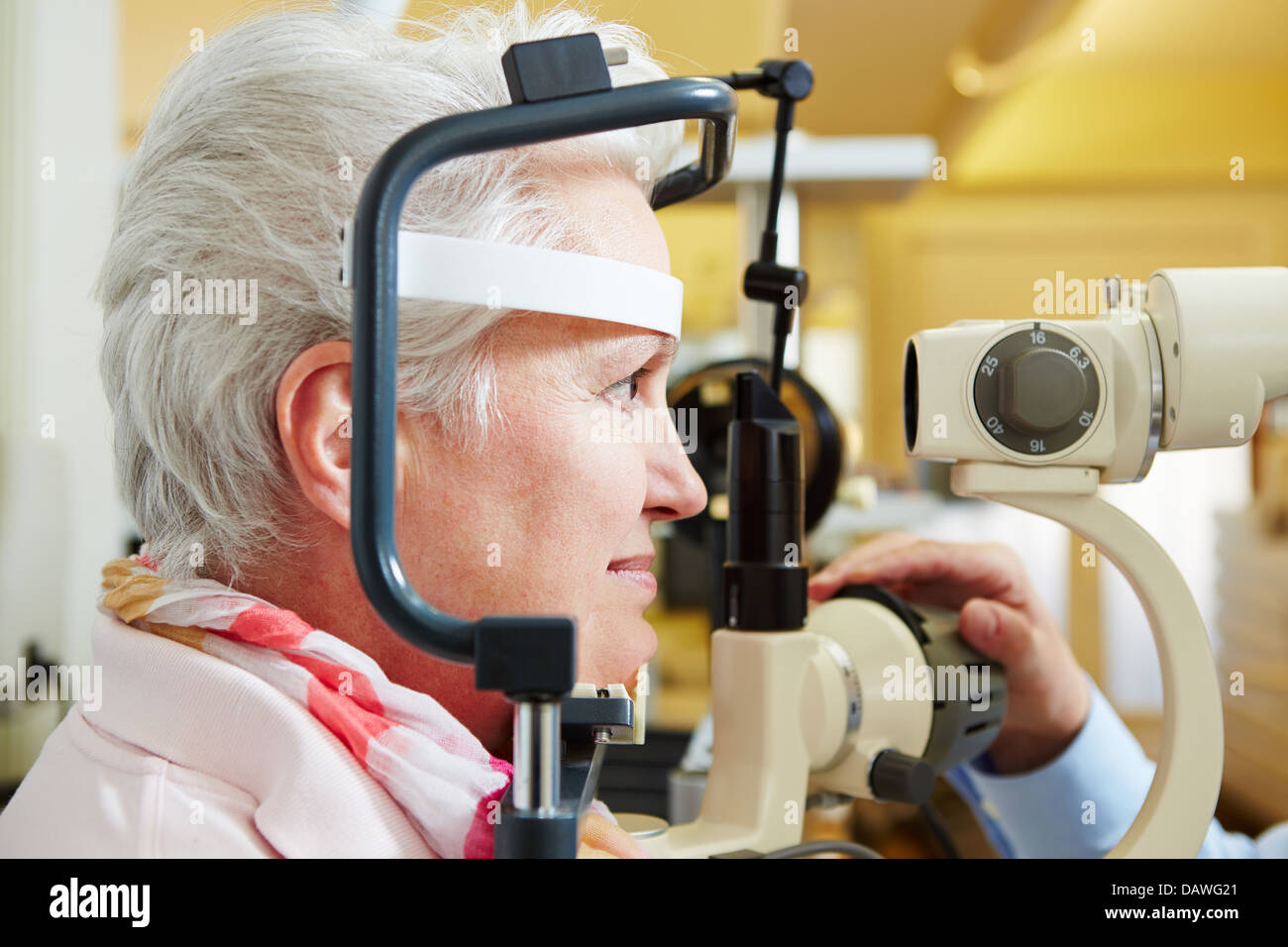 Senior woman getting her cornea checked with slit lamp at optician ...