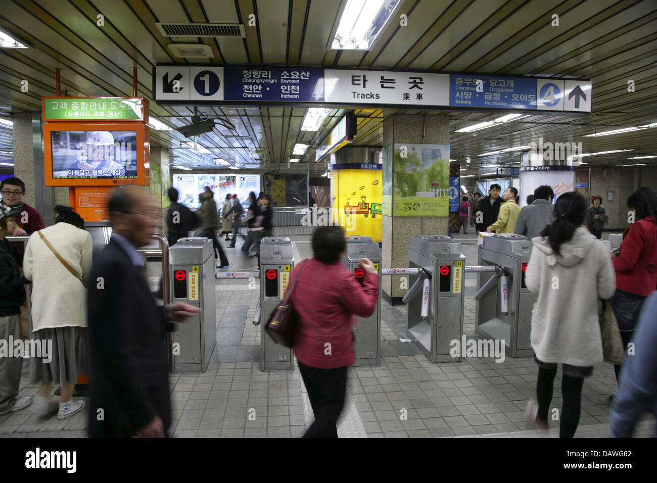 People enter the underground railway passing turnstiles in Seoul ...