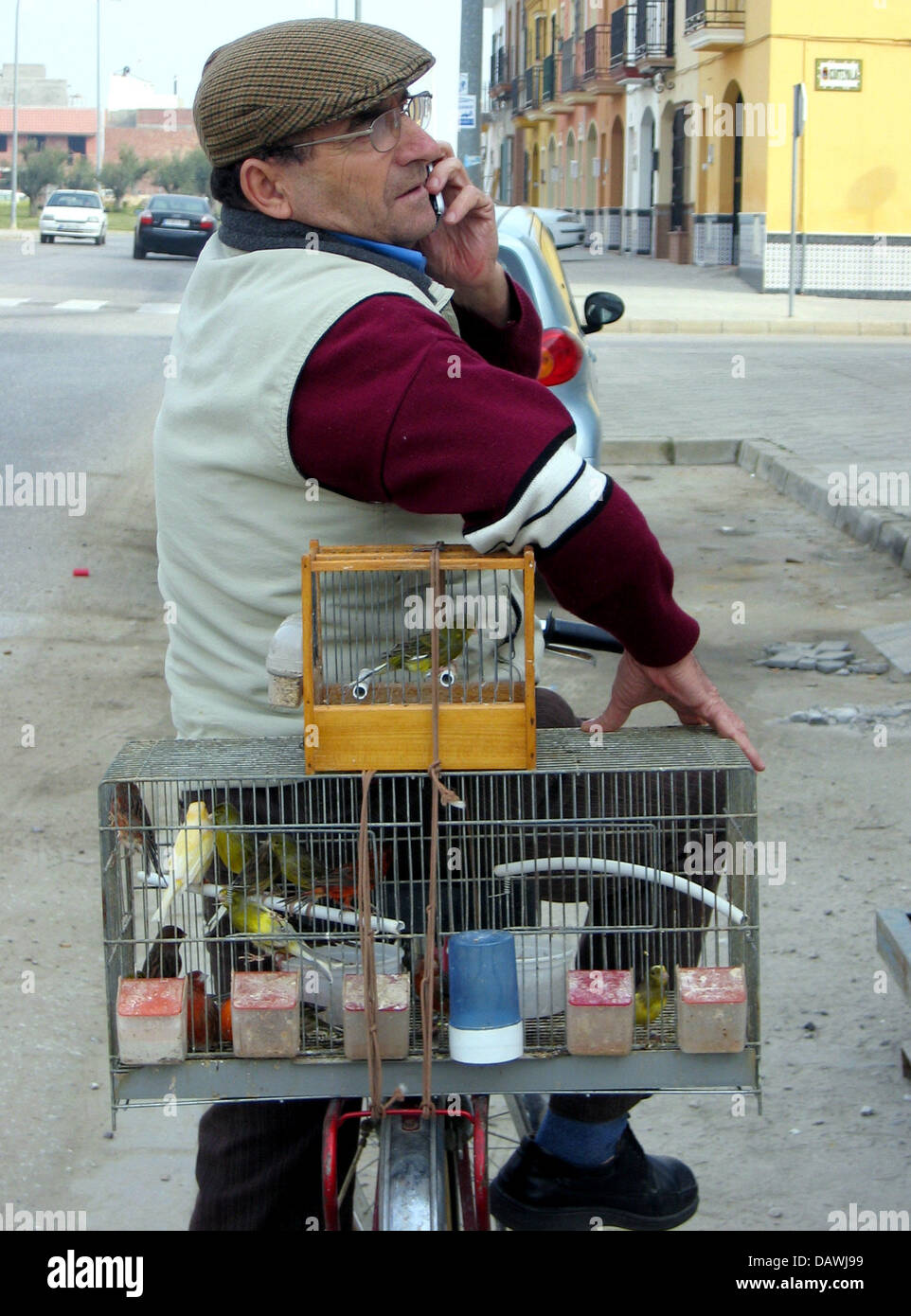 A bird vendor talks on his mobile phone while transporting birds in ...