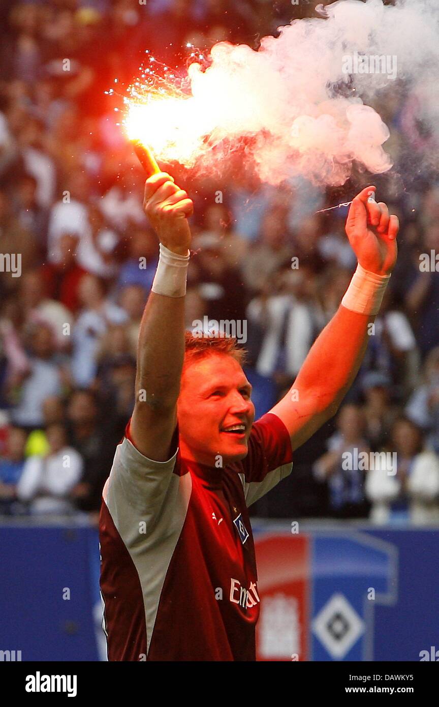 Hamburg's goalkeeper Frank Rost holds up a burning firework as he ...