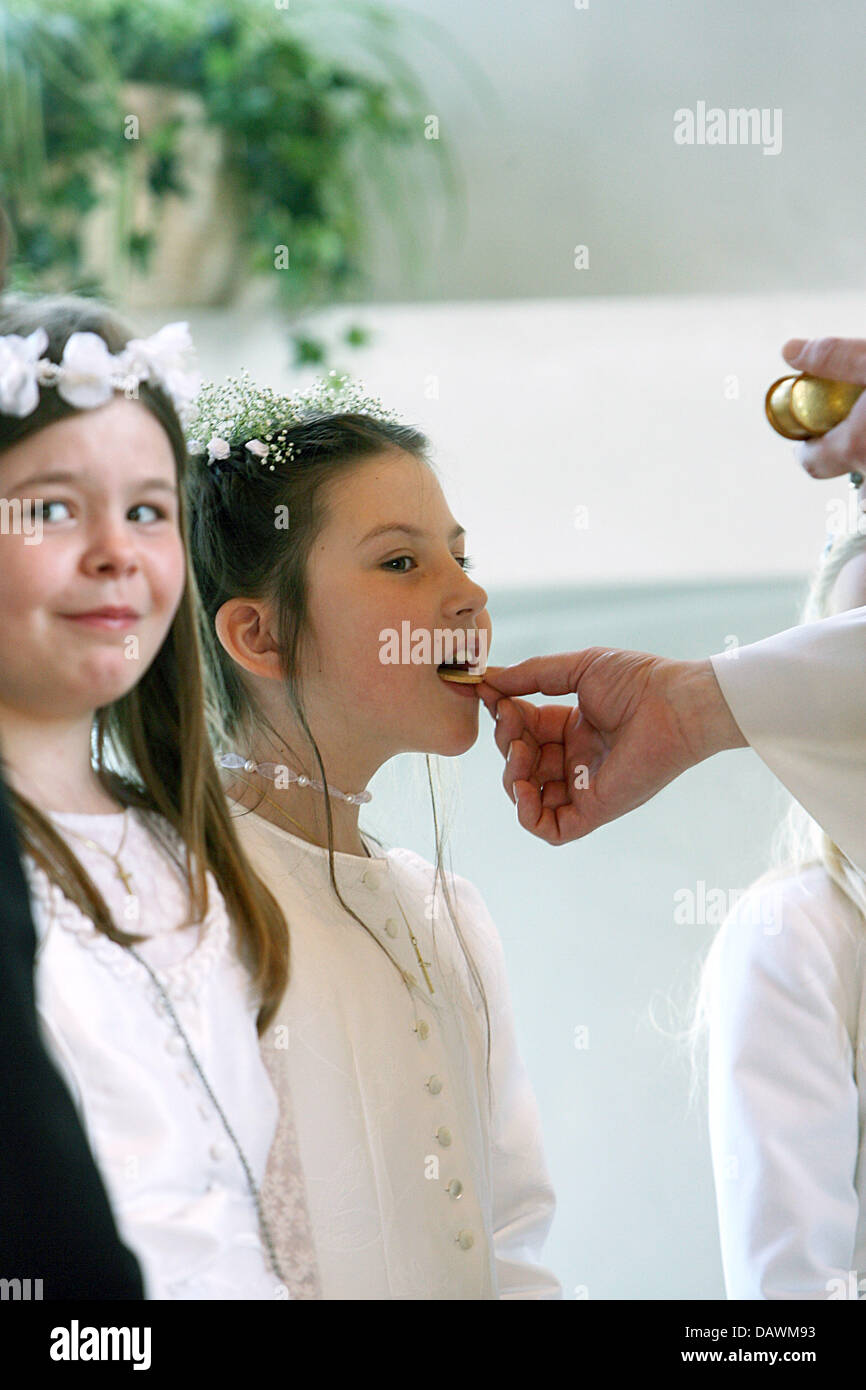 A girl receives the eucharistic bread during her First Communion in ...