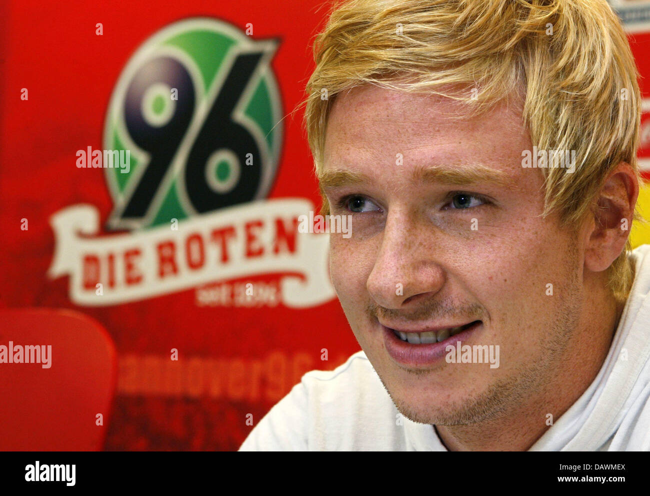 German international forward Mike Hanke smiles in front of the logo of ...