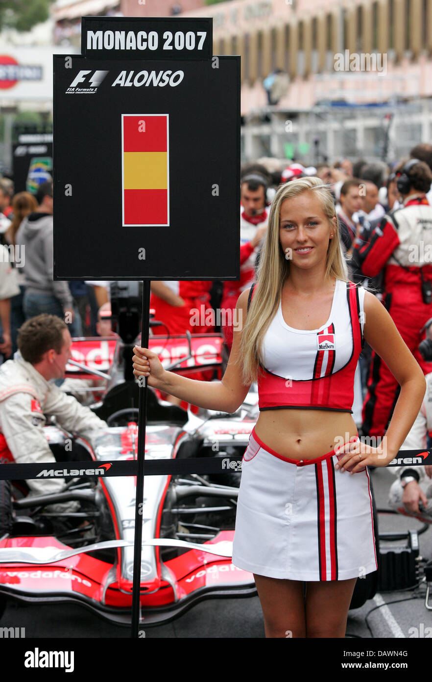 A grid girl poses in front of Spanish Formula One pilot Fernando Alonso ...