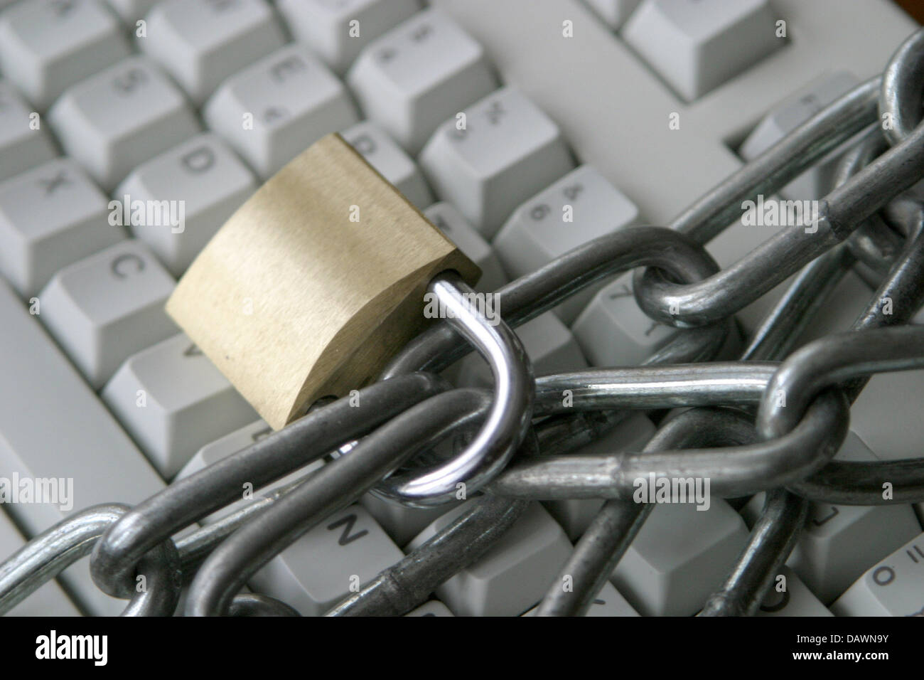 A steel chain connected by a padlock lies on top of a computer keyboard ...
