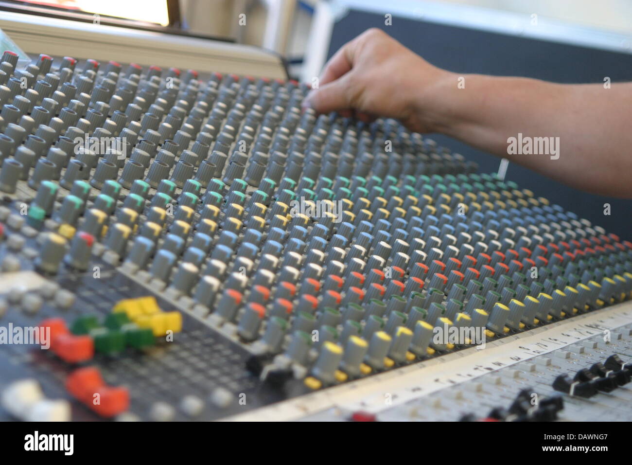 A man operates a mixing console with various colourful buttons during ...